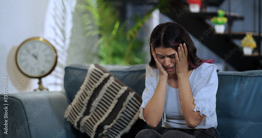 Indian tired tense abuse afraid young female girl sitting sofa couch ...