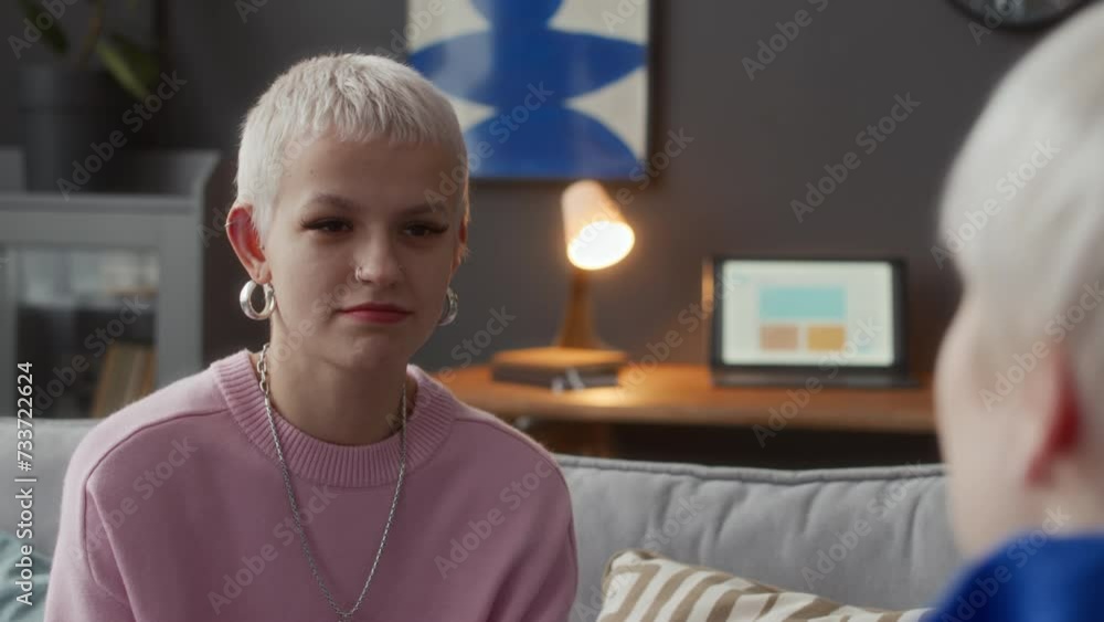 Over shoulder of short-haired young blond woman speaking with ...