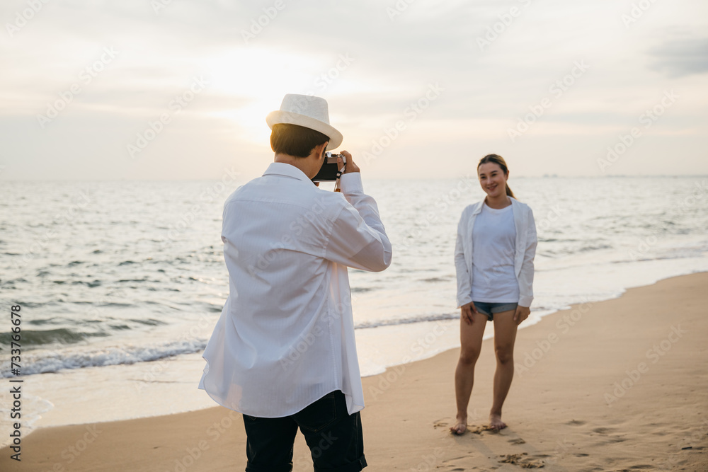 Romantic sunrise at beach for young couple in white as boyfriend takes ...