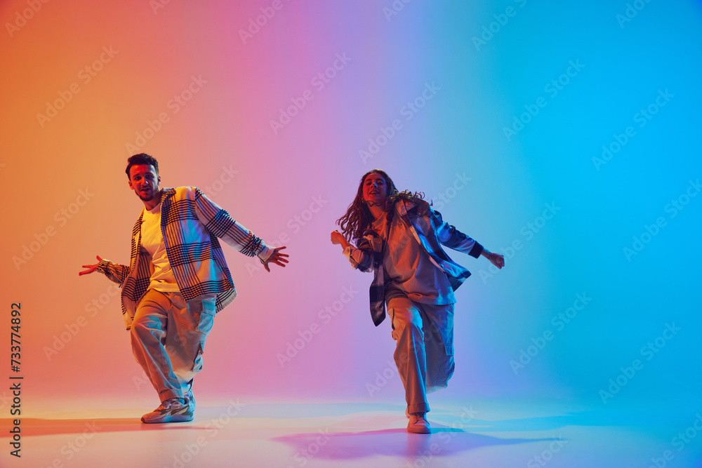 Dynamic duo, man and woman, mid-dance in vibrant neon against gradient ...