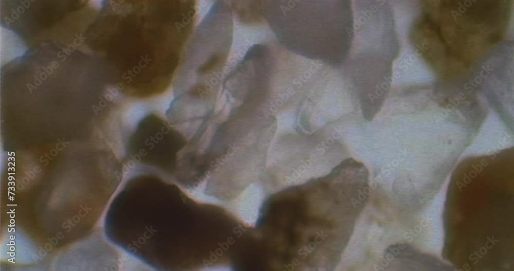 Videotape of rocks with bacteria under a microscope. Crystals with ...