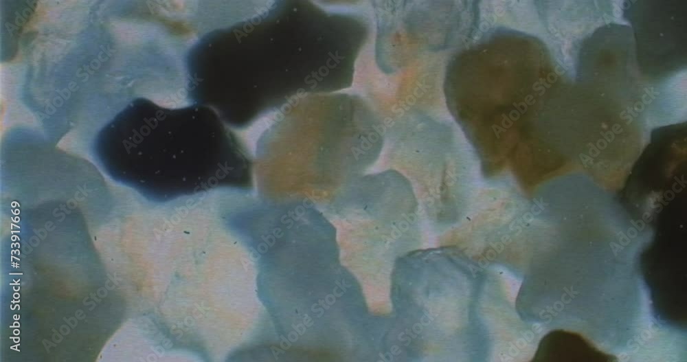Videotape of rocks with bacteria under a microscope. Crystals with ...