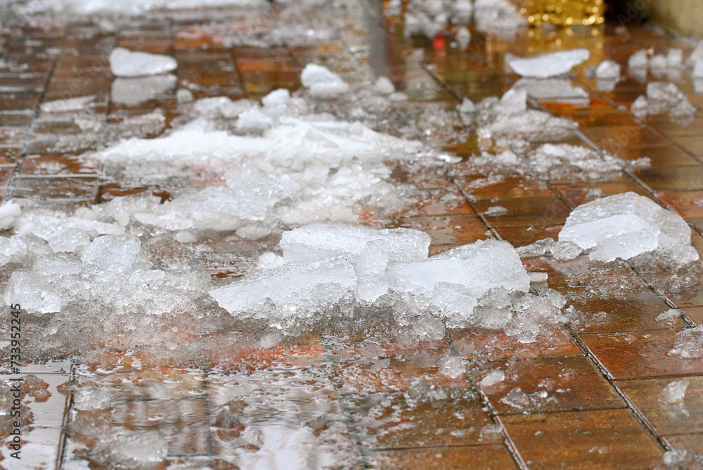 Ice and snow melting on paving slabs, ice thaw on sidewalk. Wet and ...