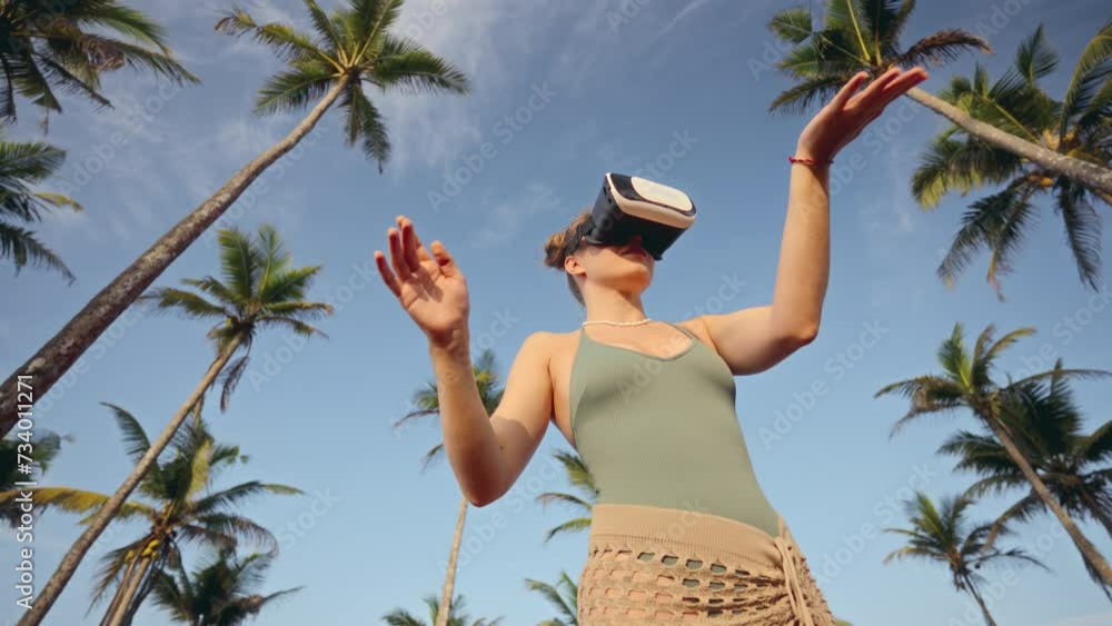 Woman uses VR headset outdoors, immersed in virtual simulation. Arms ...
