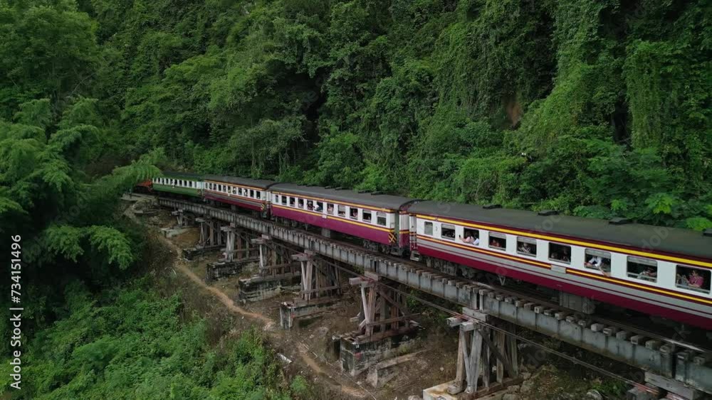 Drone footage of a train moving along a viaduct along a vertical wall ...