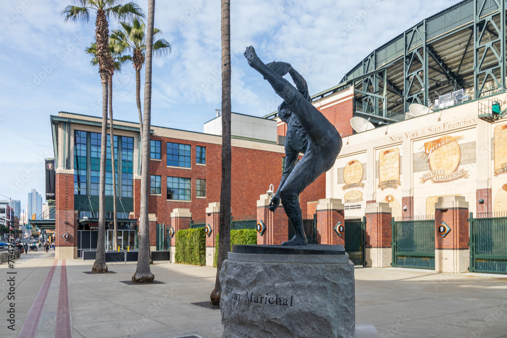 a statue of Juan Marichal in front of Oracle Park with office buildings ...