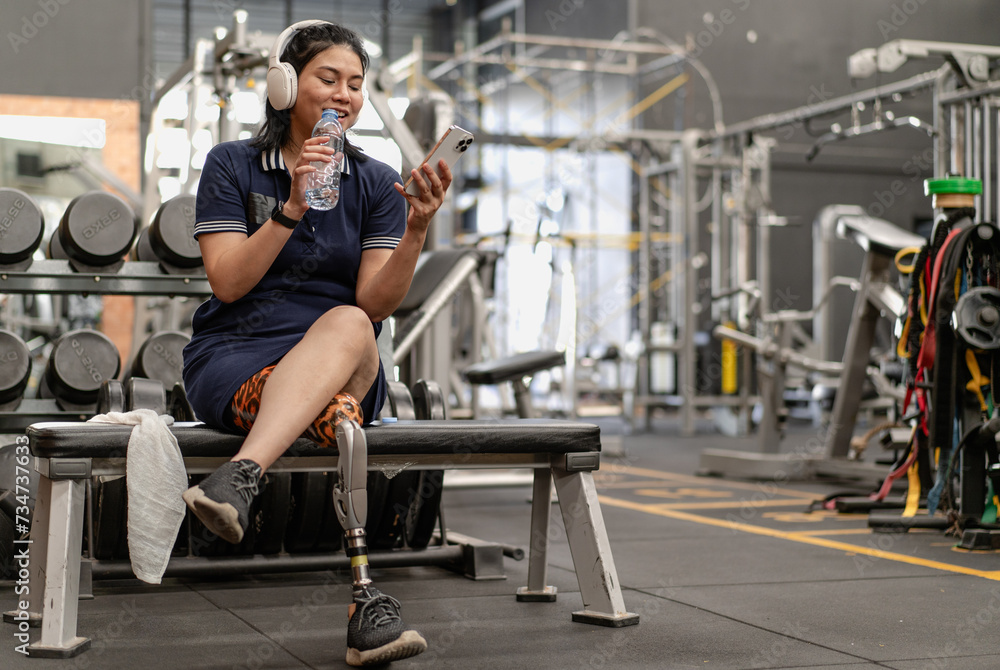 Confident woman with artificial leg exercising in fitness gym ...