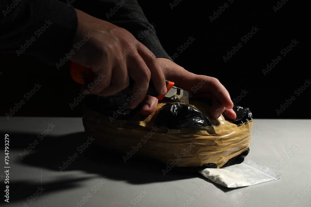 Smuggling and drug trafficking. Man opening package of narcotics with ...