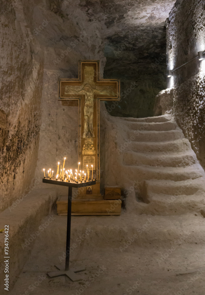 Inside the cave next to the church there is a cross and burning candles ...