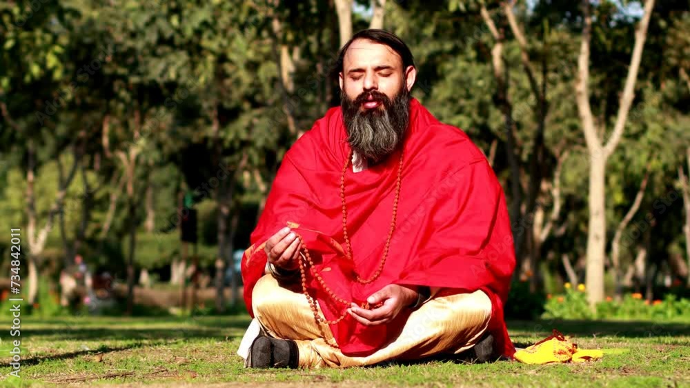 Beard yogi of Indian ethnicity chanting mantras sitting in lotus ...