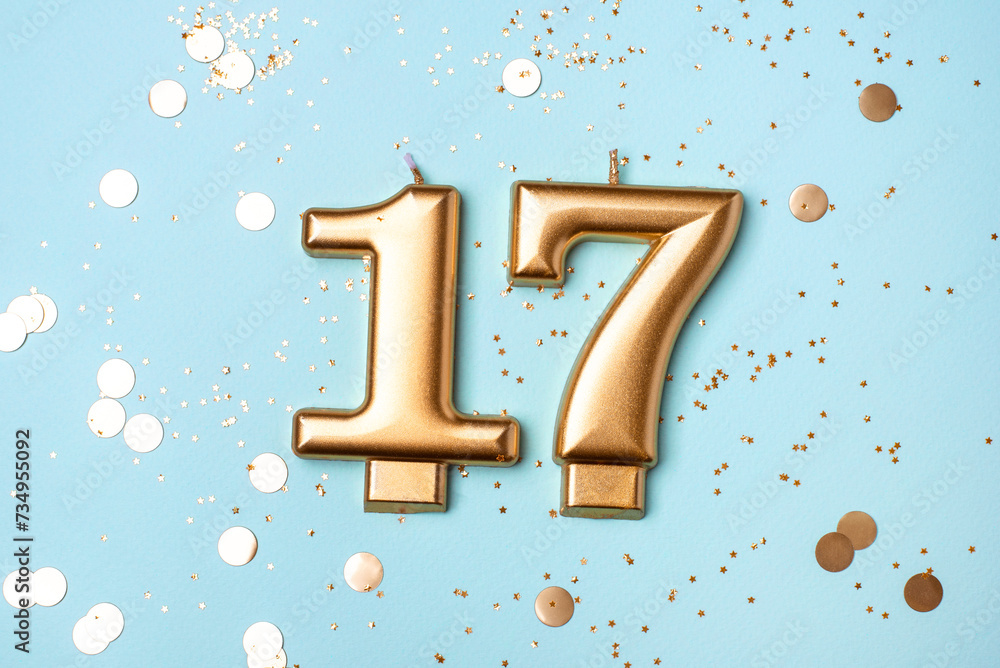 Gold candles in the form of number seventeen on blue background with ...