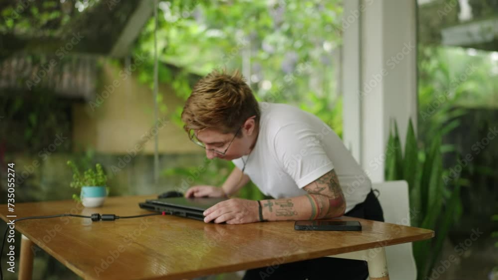 Transgender individual begins work on computer in well-lit modern ...