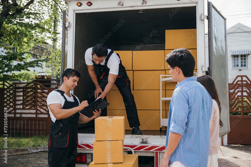 Professional movers assist a satisfied newlywed couple who sign the ...