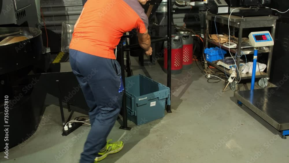 Vidéo Stock Man places plastic container under coffee roaster machine ...