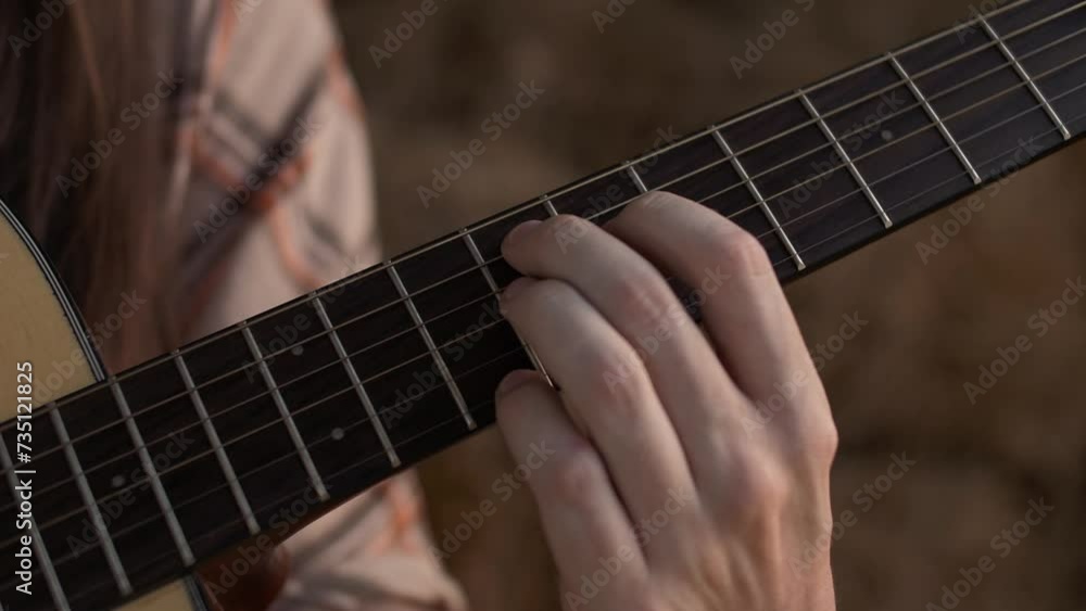 The musician's fingers glide across the fingerboard of an acoustic ...