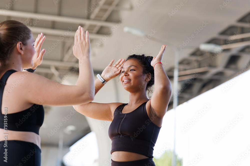 Young smiling female giving five to her fitness buddy. Two plus-size ...