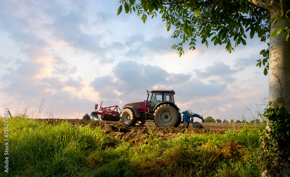 Agriculteur au volant de son tracteur labourant les champs au printemps ...