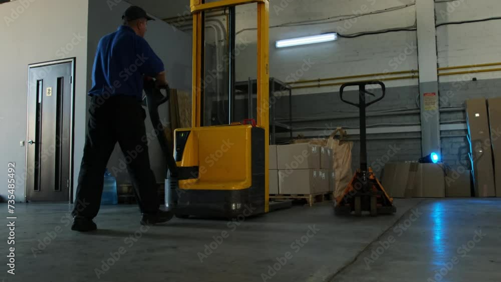 Man worker operates forklift to lift boxes in storehouse. Skilled man ...