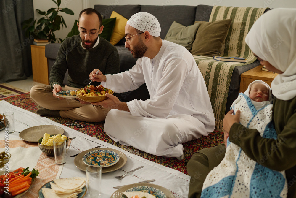 Young Muslim man in white kandora sitting on the floor of living room ...