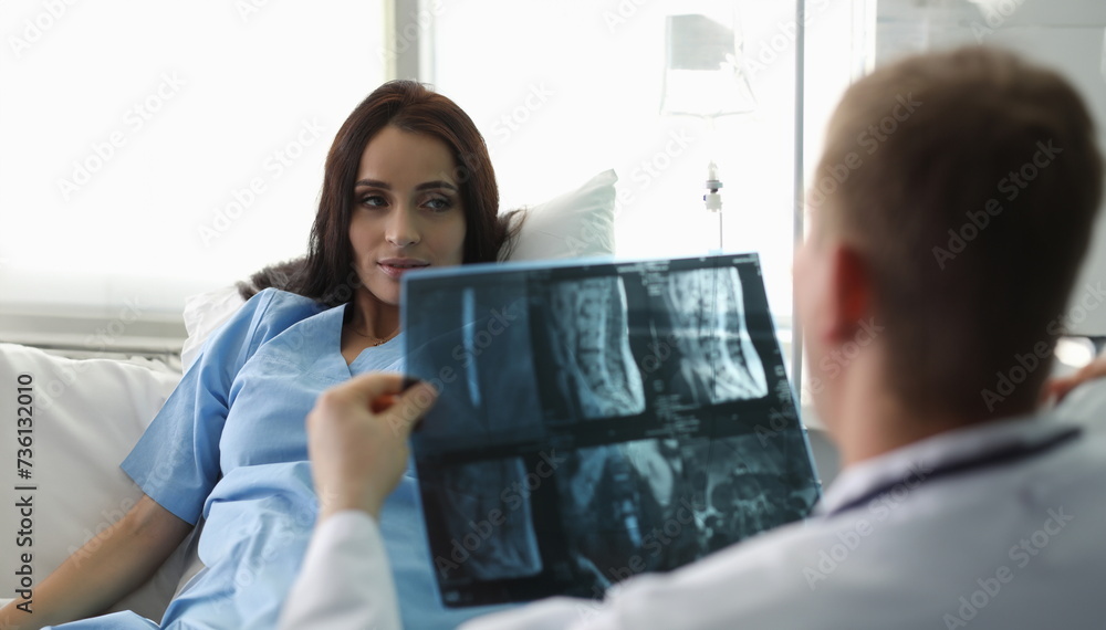 Patient lying on bed looking at doctor with x-ray. Emergency medical ...
