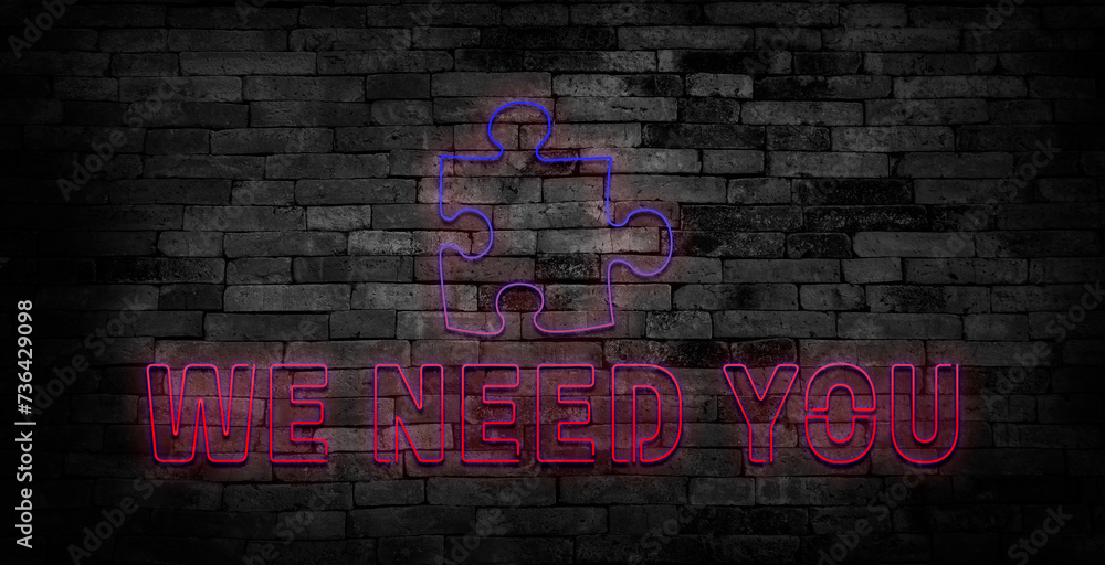 We need you. Neon sign. Brick wall at night with the text "We need you ...