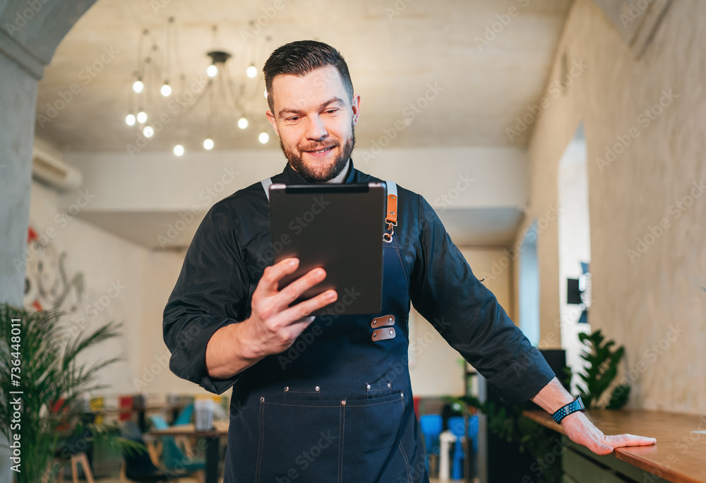 Smiling small business owner dressed in a black chef uniform with an ...