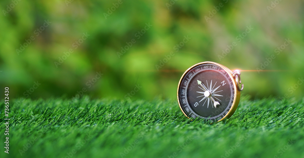 Gold compass on green grass in the garden background with sunshine ...
