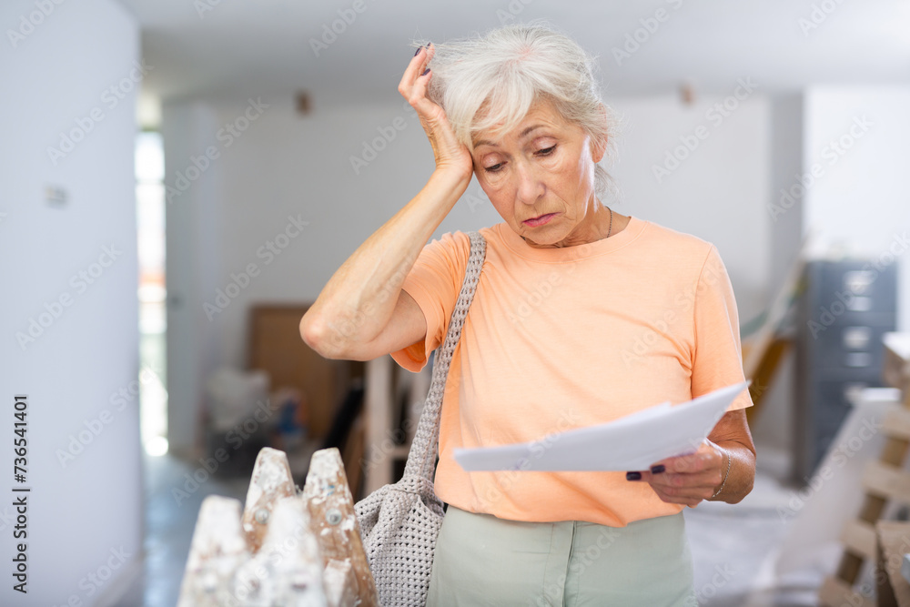 Stressed mature woman homeowner examining room under reconstruction ...