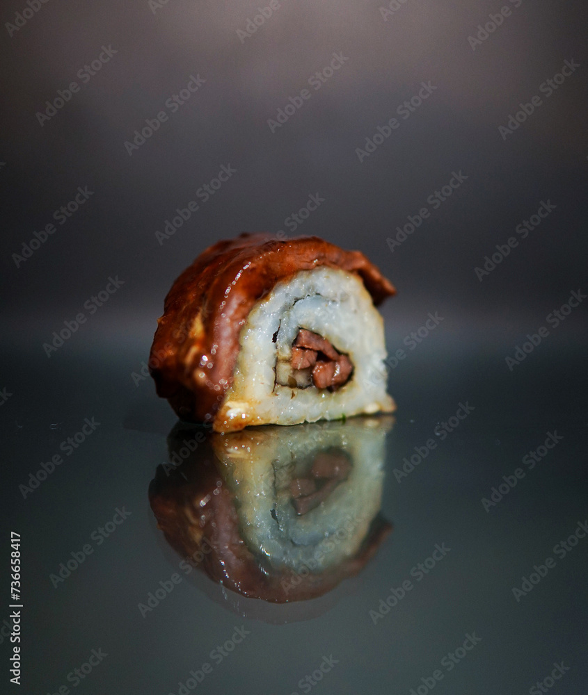 Beef teriyaki roll served on a black wooden plate, avocado, cucumber ...