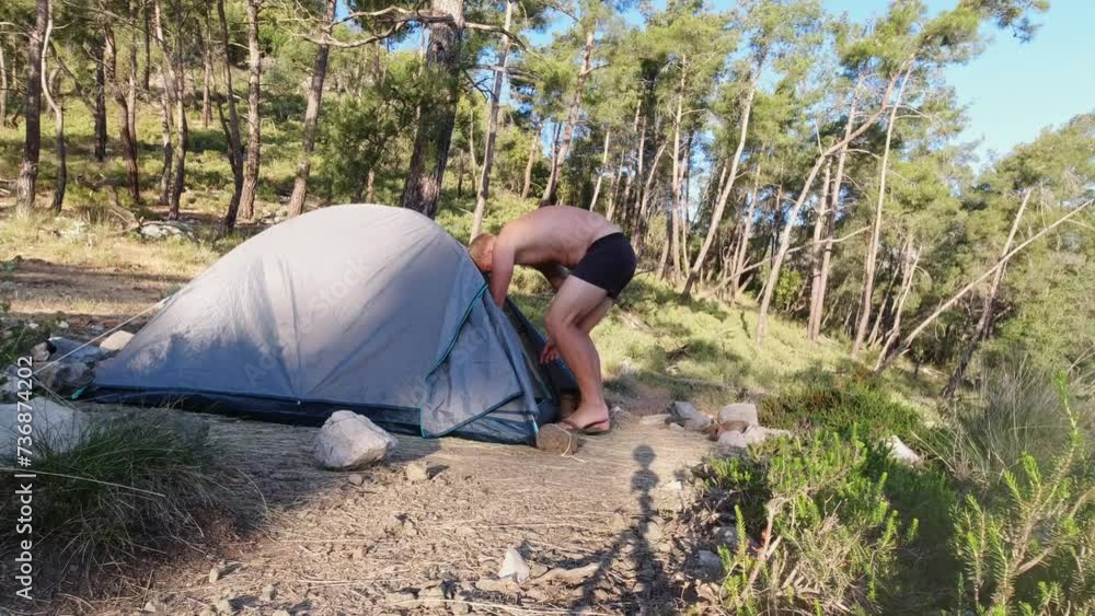 Walking towards his tent, an adventurous camper has set up hi temporary ...