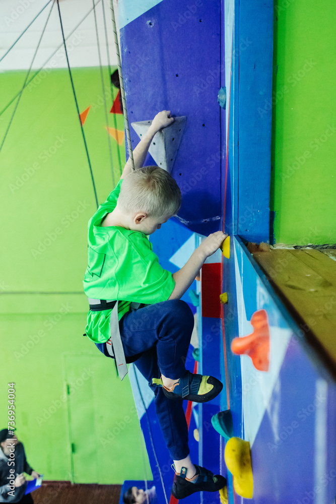Rock climbing for children. Blond boy in a green shirt is climbing ...