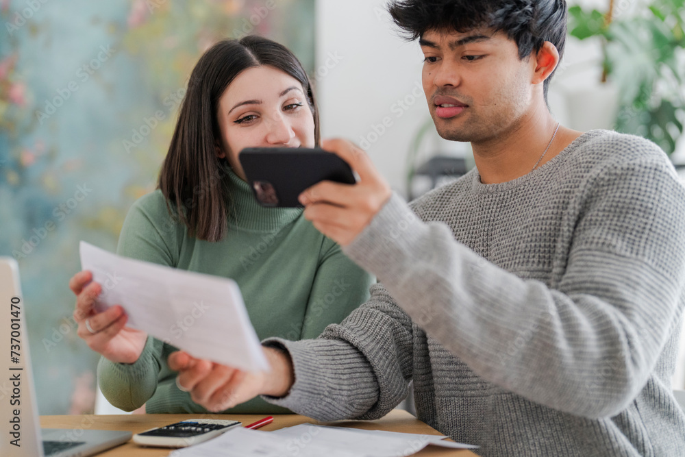 A young man captures an image of a paper document using his smartphone ...