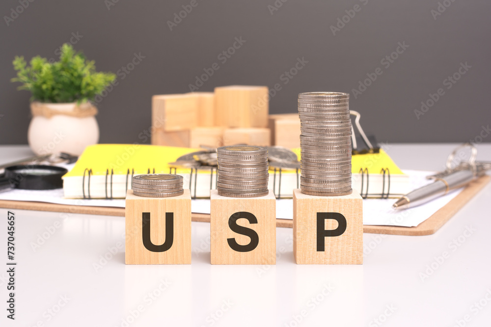 USP text in wooden blocks with coins stacked in increasing stacks ...