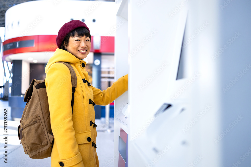 Female passenger with backpack printing boarding pass at self-service ...
