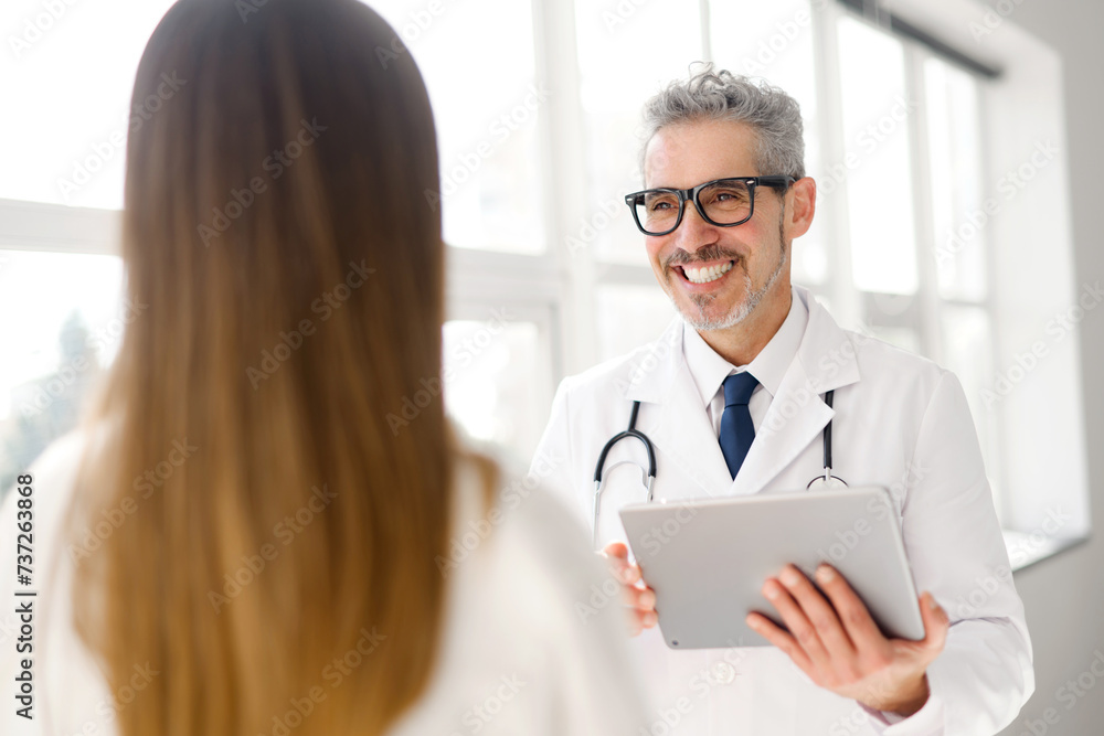 A distinguished doctor with grey hair is shown holding a tablet and ...