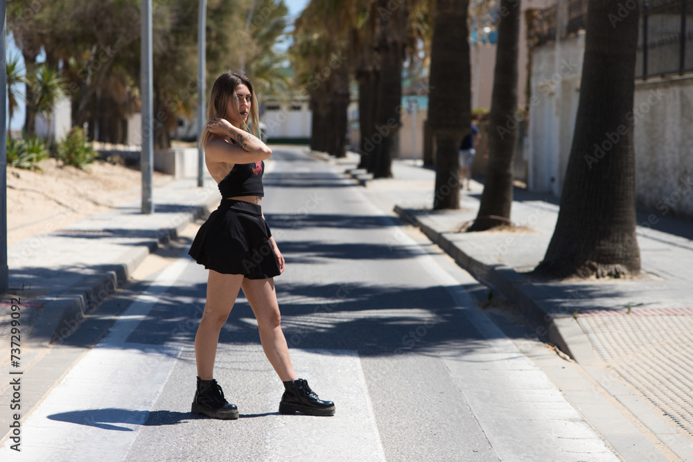 Blonde, young and beautiful woman dressed in black skirt and black top ...