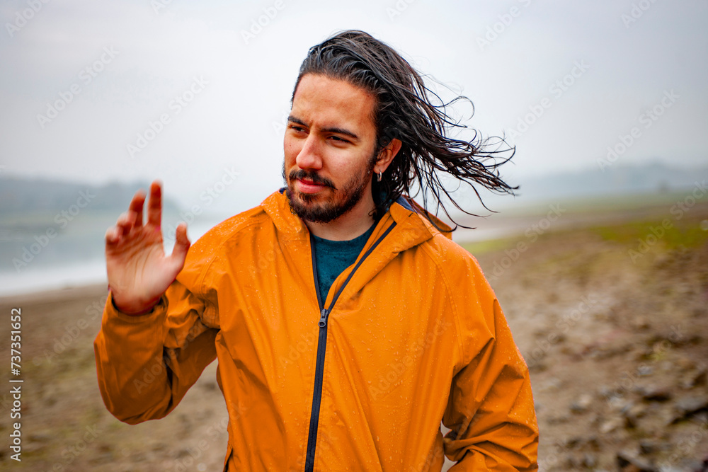 Long haired man standing in a rain soaked landscape shaking his head ...