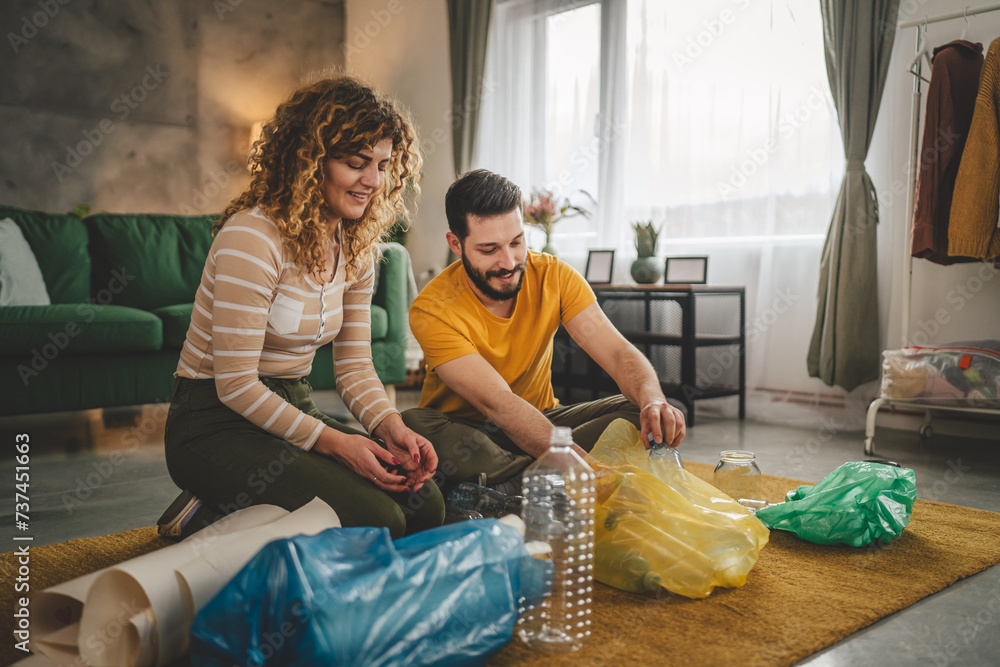 husband and wife recycle at home sorting waste plastic paper and glass ...