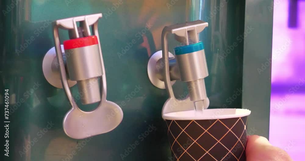Male hand holding paper cup and pouring cold water from cooler. Using ...