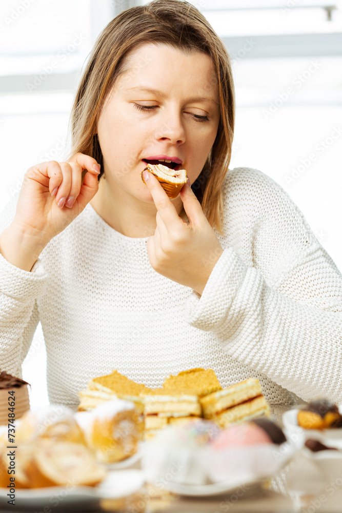 Woman eating pastry with cream, picking what to eat sitting beside ...