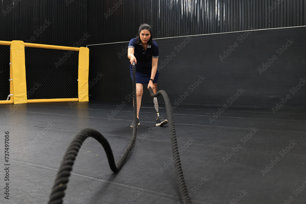 Strong disabled woman doing rope workouts in the gym or fitness ...