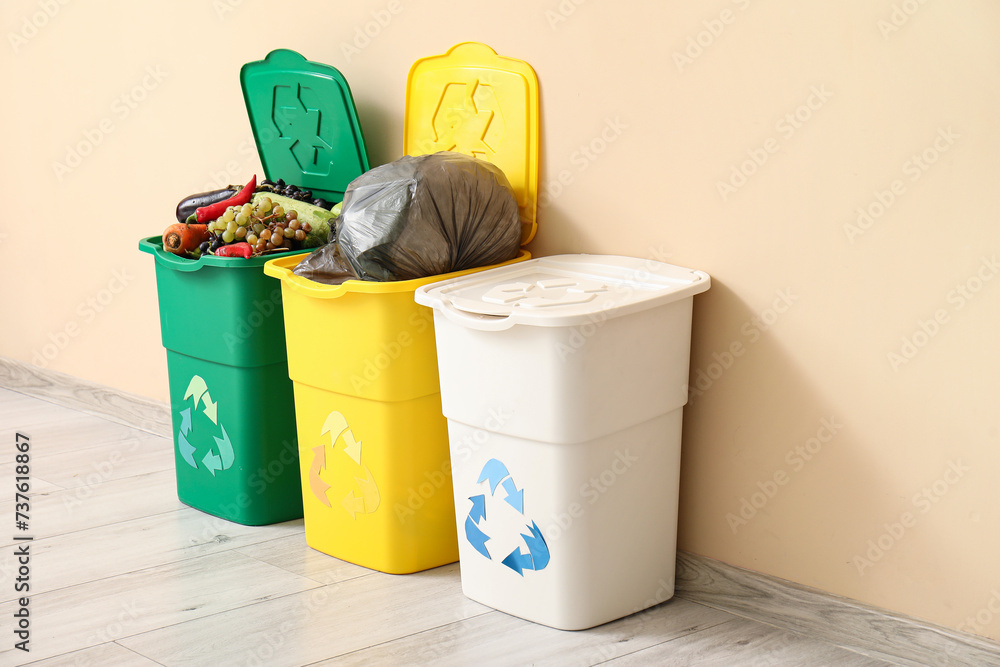 Containers for trash with food waste and full garbage bag near beige ...