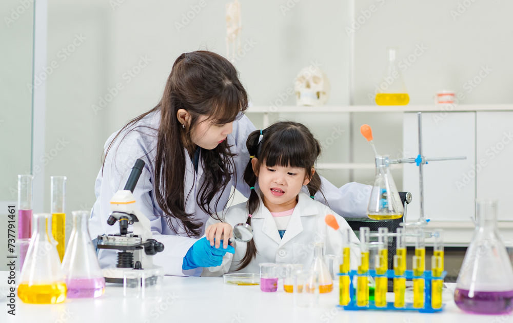 Asian woman scientist and little girl looking through magnifying glass ...