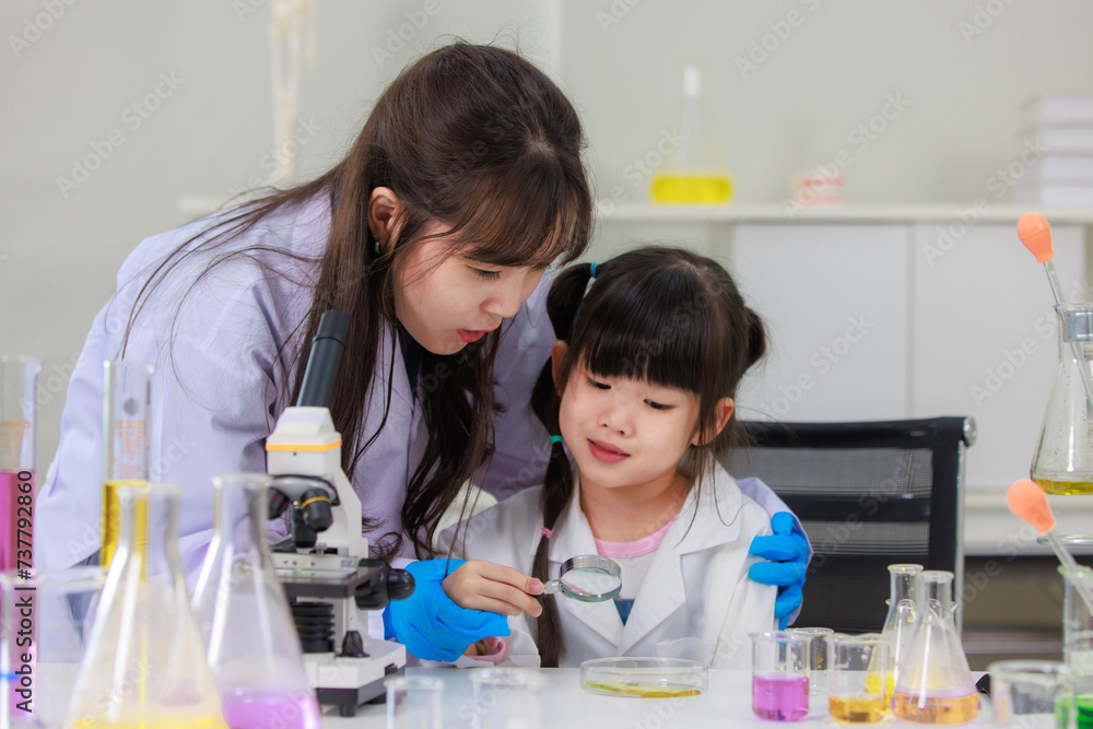 Asian woman scientist and little girl looking through magnifying glass ...