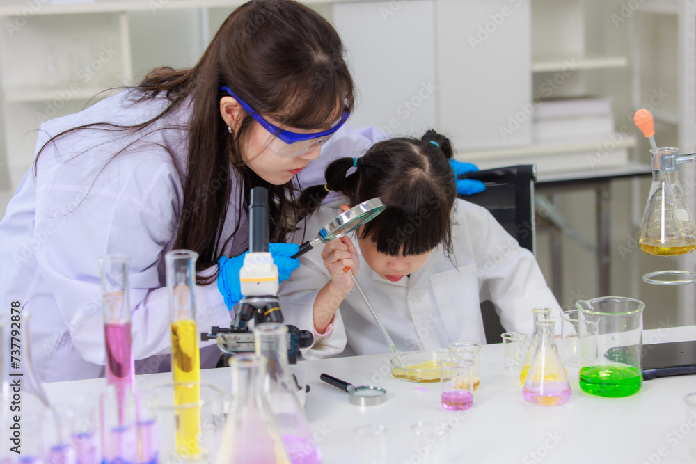 Asian woman scientist and little girl looking through magnifying glass ...