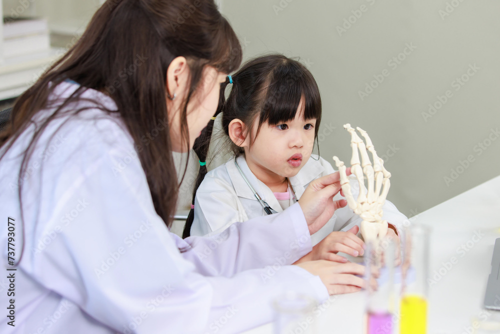 Asian woman doctor physiotherapist explains human fake body skeleton ...