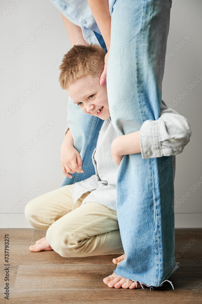 Young happy boy hugging mom's legs. Hyperactive kid holding his mother ...