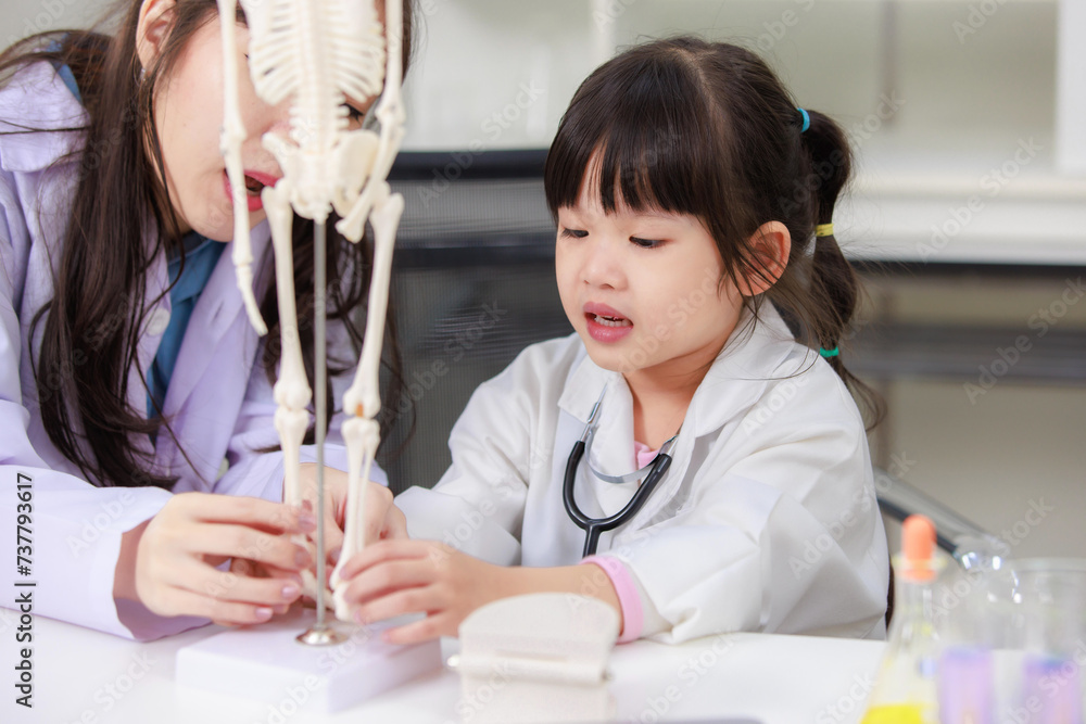 Asian woman doctor physiotherapist explains human fake skeleton hand ...