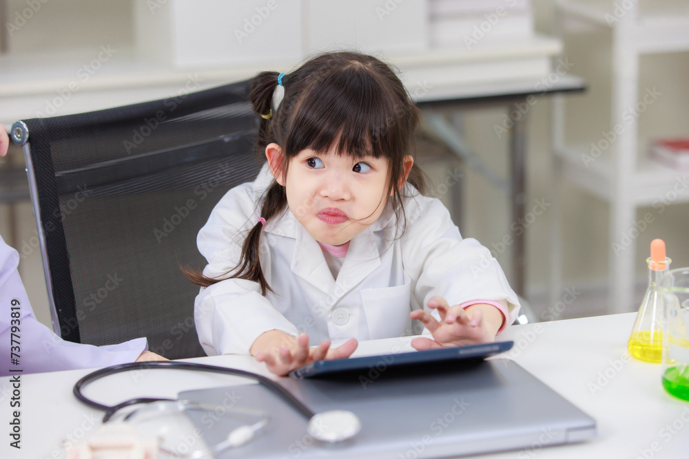 Asian little girl scientist in lab coat reading tablet computer for ...