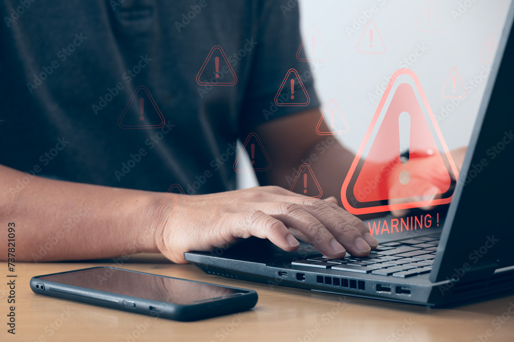 User uses laptop with warning triangle sign for error notification and ...
